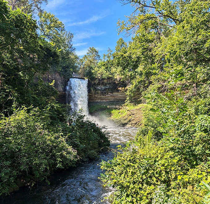 Surrounded by lush greenery, Minnehaha Falls offers a perfect frame of nature's power against a backdrop of blue sky.