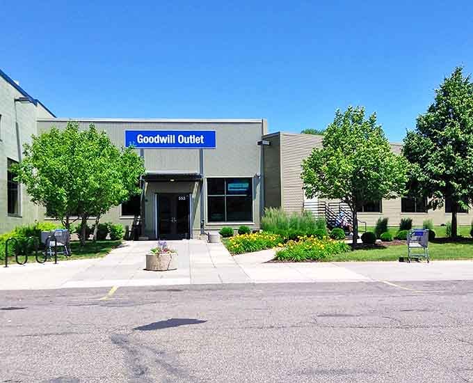 The Goodwill Outlet storefront stands ready for treasure seekers, surrounded by greenery and promising pay-by-the-pound bargains inside.