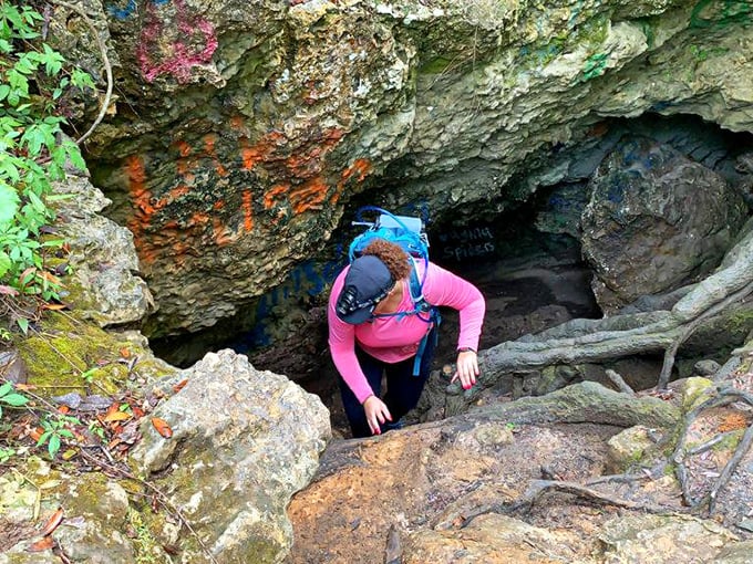 Navigating the cave entrance requires a bit of nimble footwork, as visitors squeeze through nature's doorway into a hidden limestone world.