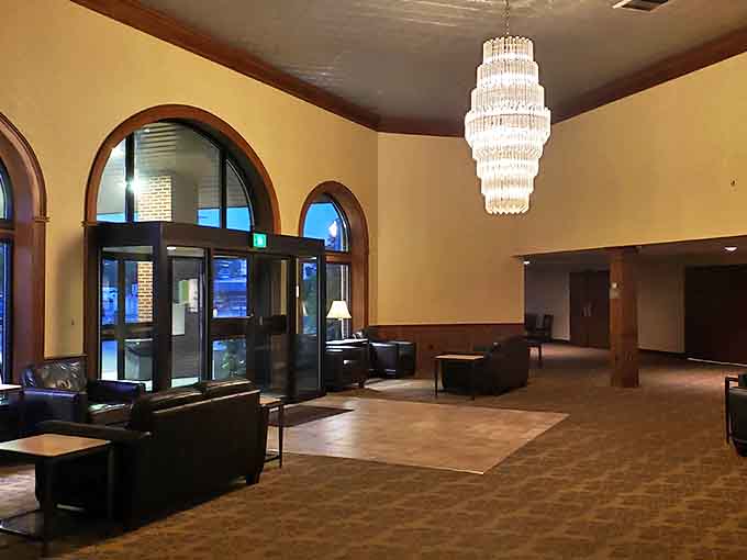 Step into the grand lobby where the magnificent chandelier casts a warm glow over patterned carpets that have welcomed guests for nearly a century.