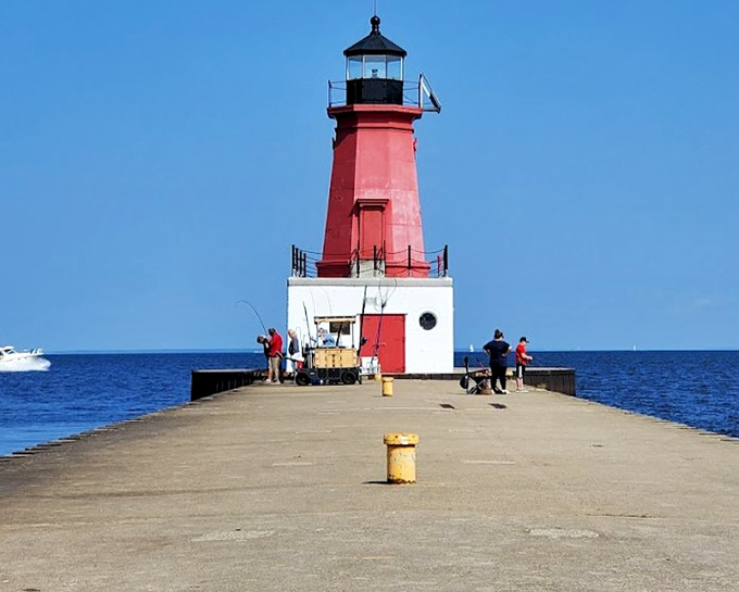 The Menominee North Pier Lighthouse stands like a crimson exclamation point against the blue horizon, guiding sailors and photographers alike.