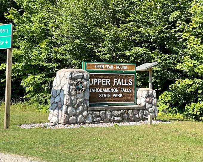 The welcoming stone entrance to Upper Falls announces your arrival at Michigan's most magnificent waterfall, promising natural wonders just beyond the treeline.