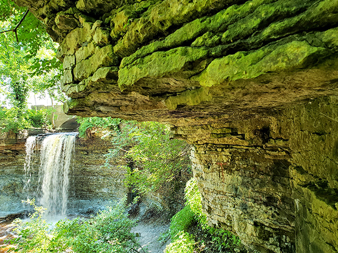 Peek beneath the rocky overhang and you'll discover nature's secret passageway, where water has carved its patient path for millennia.