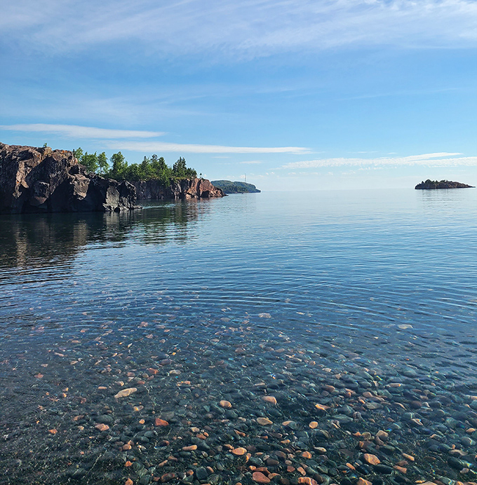 Lake Superior's crystal-clear waters reveal a kaleidoscope of colorful stones beneath the surface, like nature's own stained glass window.