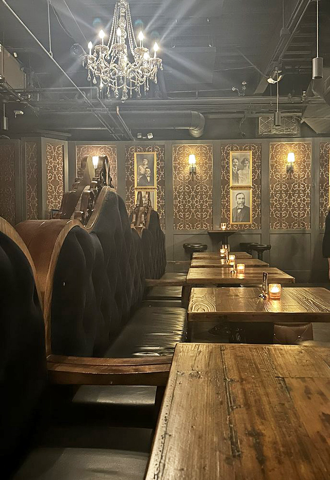 Time-travel in progress: vintage portraits watch over wooden tables while chandeliers cast dramatic shadows, creating the perfect Prohibition-era atmosphere.