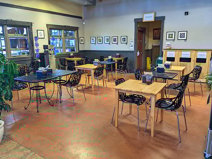 Warm wooden tables and black chairs create an inviting interior where plants and people coexist in perfect harmony.