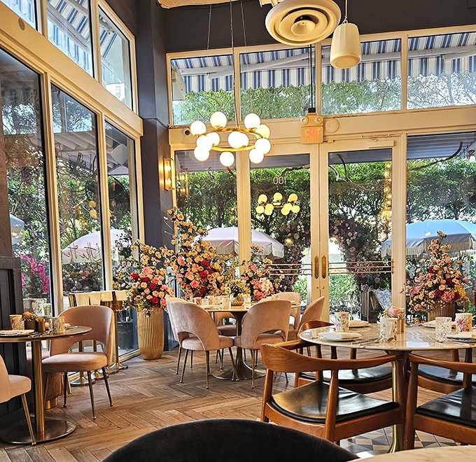 Sunlight streams through tall windows, illuminating floral arrangements that would make any botanical garden jealous. Even the chairs look like they're waiting for interesting conversation.