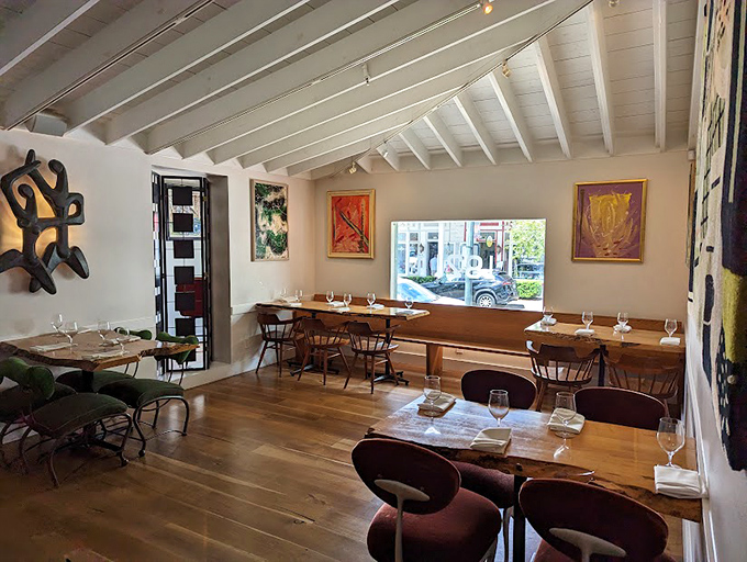 Warm wooden tables beneath white-beamed ceilings create an atmosphere where contemporary dining meets historical elegance.