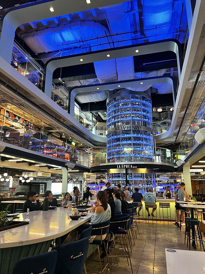 The showstopping cylindrical bar rises through all three floors, bathing the space in blue light that makes everyone look like food influencers.
