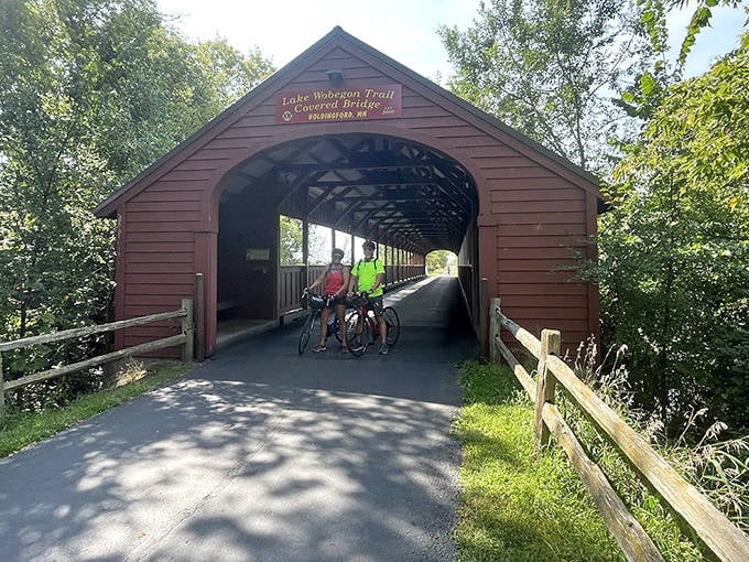 Two-wheeled adventurers pause mid-journey, framed perfectly by the bridge's wooden embrace &ndash; a postcard moment in real life.