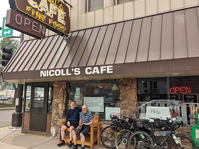 Two patrons enjoy the sunshine outside Nicoll's Cafe (now Mia's) in Pine City. The vintage "FINE FOOD" sign has been guiding hungry folks through these doors for generations.