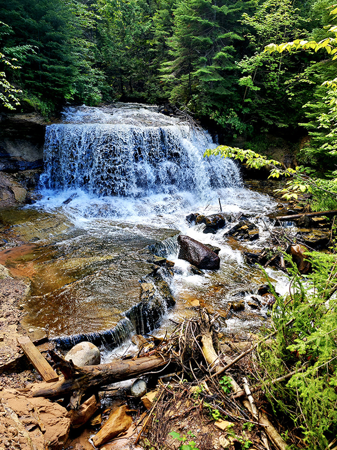 Sable Falls tumbles gracefully down sandstone steps, playing hide-and-seek through lush greenery on its journey toward Lake Superior.