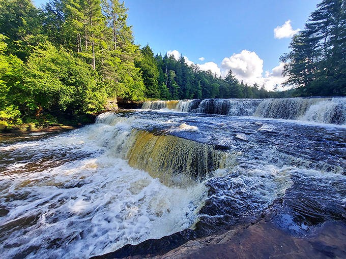 Tahquamenon's amber waters spill across the wide rocky shelf, creating a root beer-colored cascade through Michigan's pristine forest.