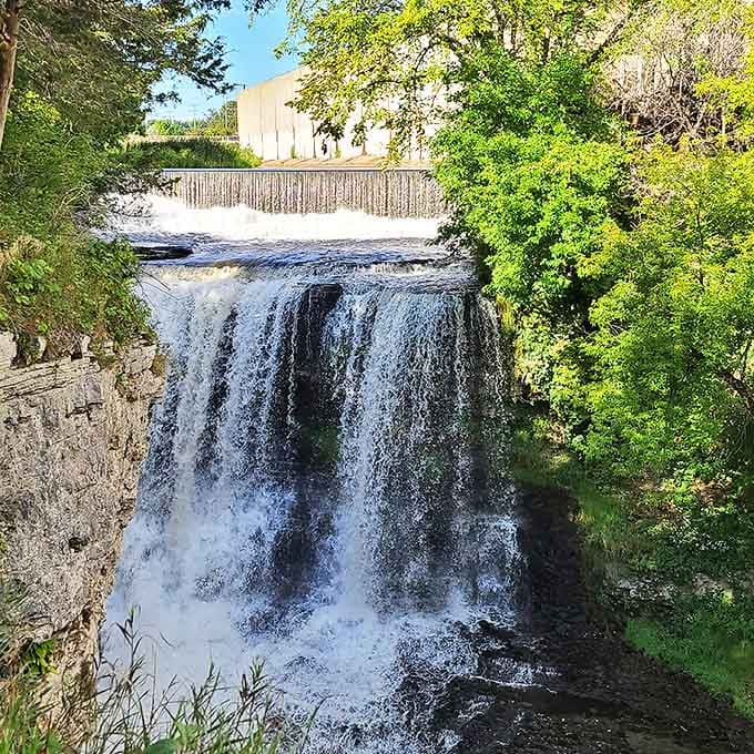 Vermillion Falls tumbles powerfully over rocky ledges, with historic structures visible above the rushing waters.