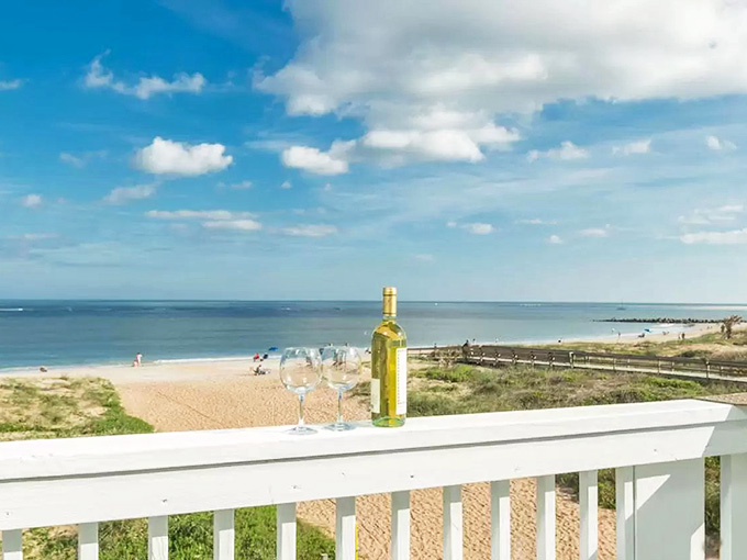 That white porch railing overlooks a beach where the wine tastes better and worries disappear with the tide.