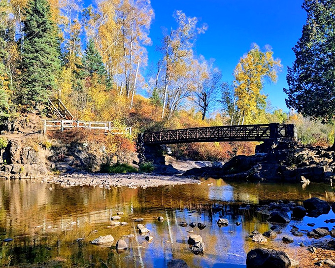 Fall colors frame the rushing waters at Gooseberry Falls, where families gather to witness one of Minnesota's most accessible and spectacular waterfalls.
