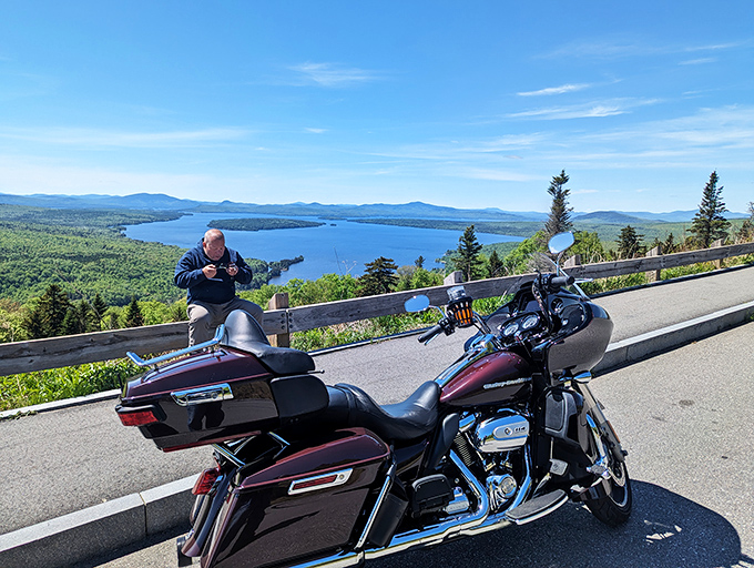 A motorcycle rests at the Height of Land overlook, where adventurers pause to soak in panoramic views that make every mile of the journey worthwhile.