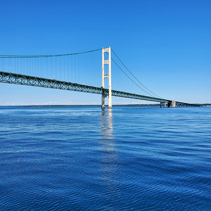 From a distance, the bridge appears to float above the horizon, its towers reaching skyward like sentinels guarding the meeting of two Great Lakes.