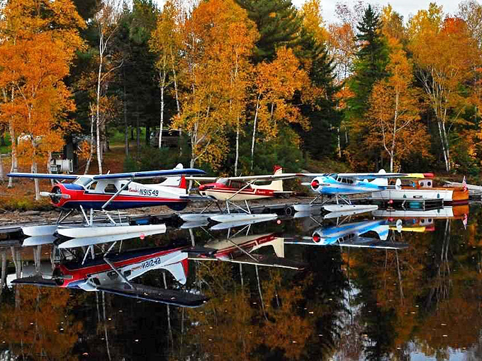 Fall's fiery display reflected in still waters – seaplanes wait patiently for their next adventure while autumn puts on its annual color show.