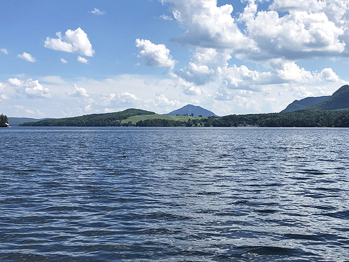 Morning light dances across the lake's surface, mountains rising like gentle giants from the misty blue horizon.