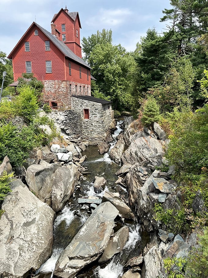 The iconic Old Red Mill stands defiant against time, its vibrant hue a perfect contrast to the rushing waters below.
