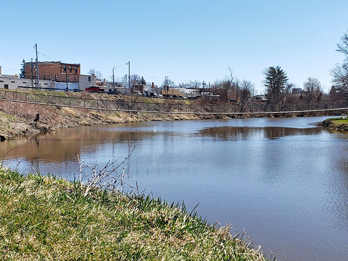 The gentle curve of the bridge against the backdrop of trees creates a postcard-perfect scene that's quintessentially Michigan.