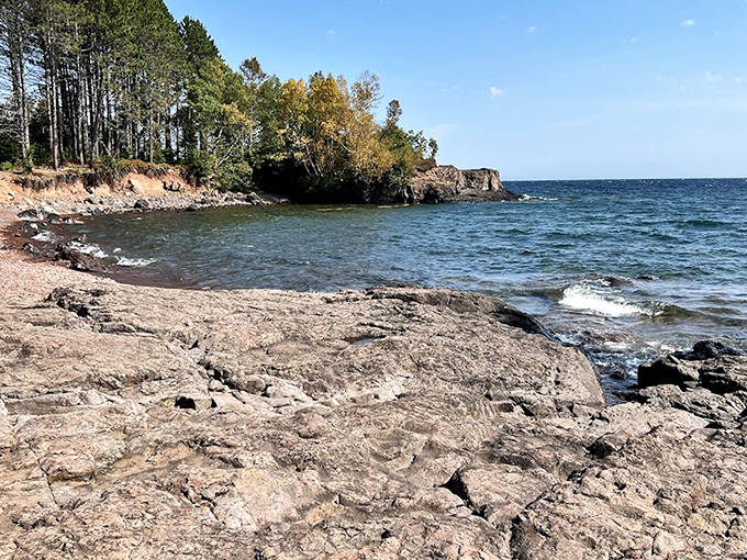 Calm waters reveal the clarity of Lake Superior, a transparent blue stage for the beach's geological performers to shine.