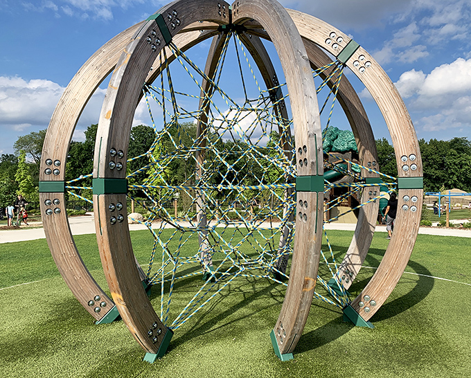 Children navigate the globe-shaped climbing structure, a world of blue and yellow ropes creating challenges for climbers of all abilities.