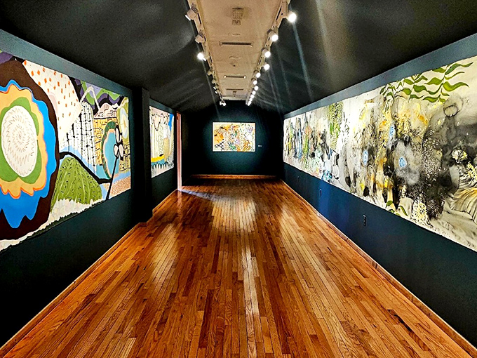 Modern art finds its perfect home in this gallery, where polished wood floors reflect contemporary visions against dramatic navy walls.