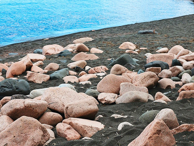 The beach's multi-colored rocks range from deep charcoal to soft pink, creating a natural mosaic that beachcombers can admire for hours.