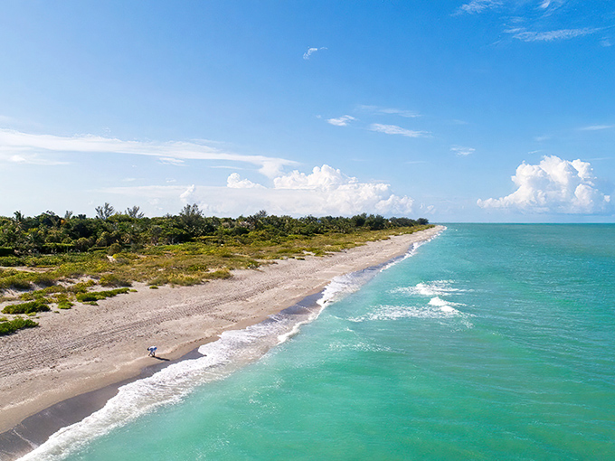 Captiva Island's pristine shoreline stretches into the distance, where turquoise waters meet powder-white sand under a sky painted with dramatic clouds.
