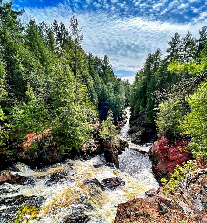 Copper Falls' rust-colored waters flow through a dramatic gorge, creating multiple cascades that contrast beautifully with the surrounding pine forest.