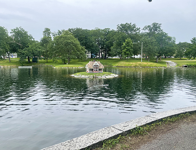 Deering Oaks Park's serene pond creates a perfect mirror image of its surroundings, the small stone house adding fairy-tale charm.