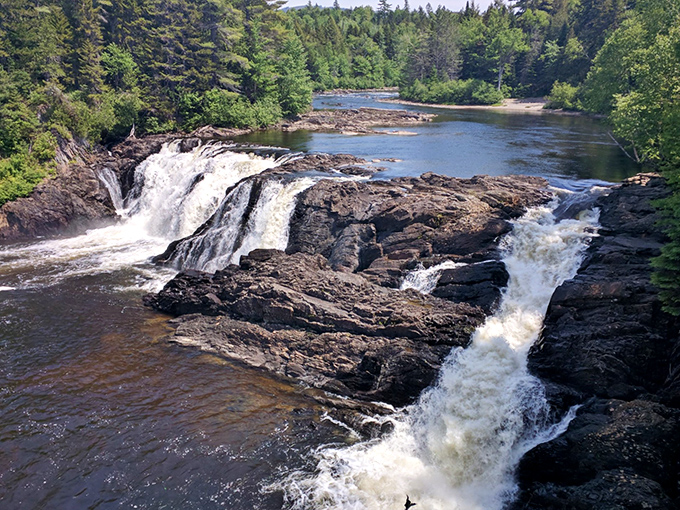 Rushing water cascades over ancient rocks at one of Maine's spectacular waterfalls, creating nature's perfect swimming spot on hot summer days.