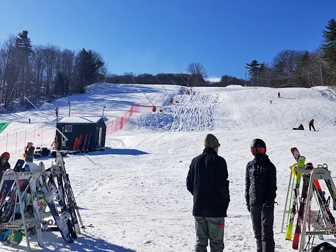 Skiers enjoying the slopes at Camden Snow Bowl with perfect powder conditions and stunning mountain views on a bright winter day.