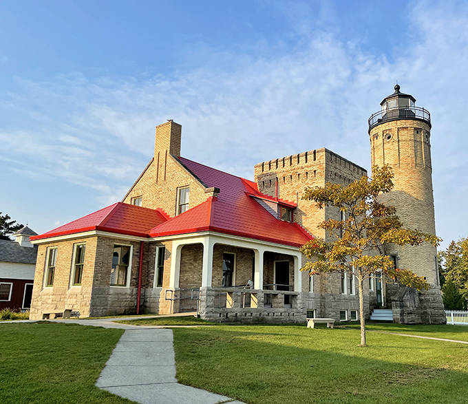 Old Mackinac Point Lighthouse stands sentinel with its distinctive red roof and limestone walls. This historic beacon has guided ships through the straits since 1889.