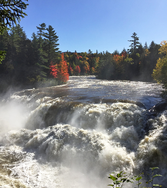 Maine's waterfalls transform in autumn, when surrounding trees burst into fiery colors that contrast dramatically with the powerful white water.