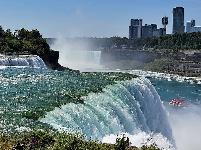 The iconic horseshoe curve of Niagara Falls creates a misty backdrop for the city skyline, showcasing nature's power alongside human ingenuity.