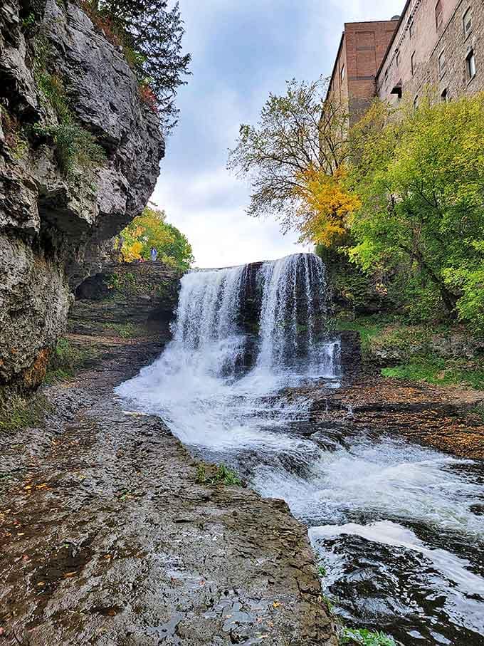 The falls' dramatic drop creates a misty curtain against historic stone walls, nature's power display in downtown Hastings.