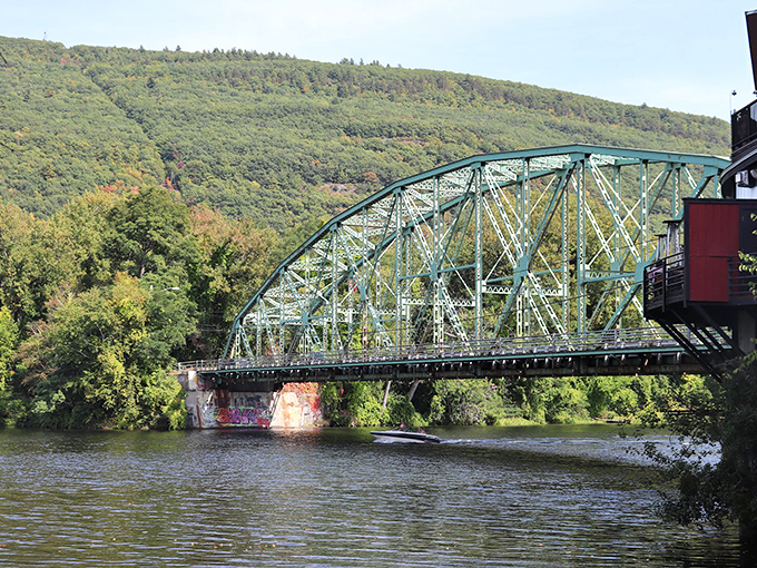 The green bridge arches over the Connecticut River like a portal to another era, connecting Vermont to New Hampshire while providing views that justify stopping mid-crossing despite traffic.