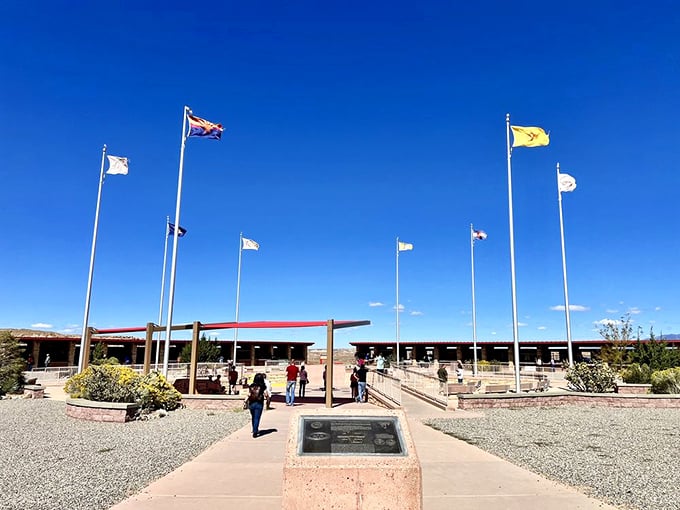 Flags representing the four states and Native nations flutter against dramatic desert skies at this unique intersection.