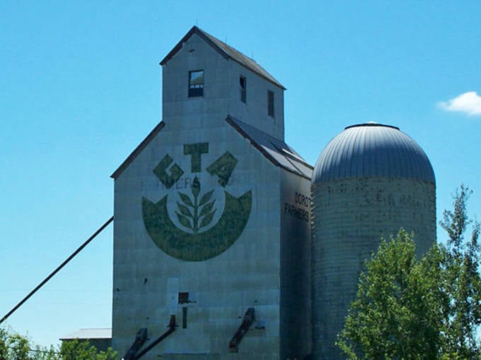 The weathered GTA grain elevator dominates Dorothy's skyline, a monument to the agricultural foundation that built communities across America's heartland.