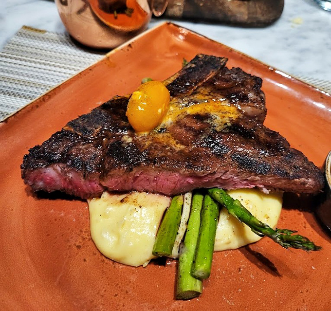 Perfectly seared steak rests on creamy mashed potatoes with asparagus spears standing at attention &ndash; a plate that demands respect.