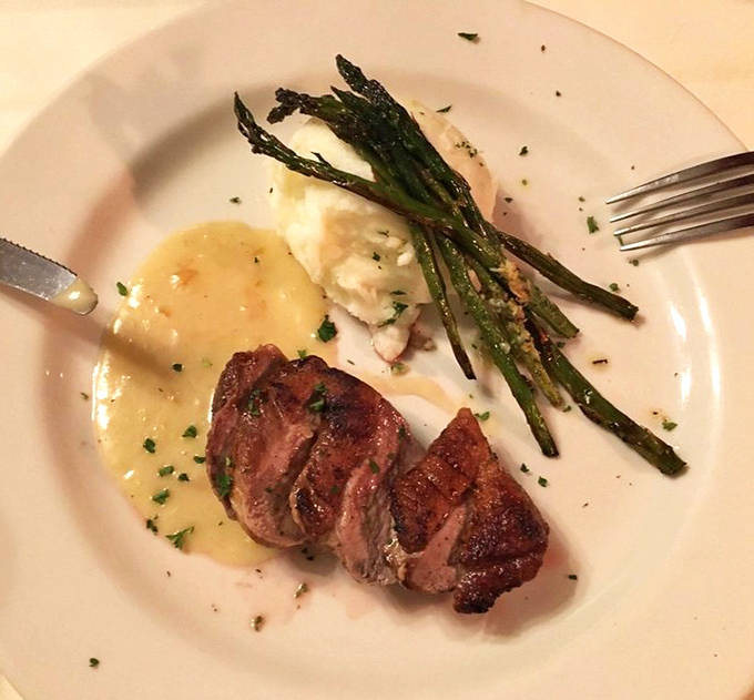 Duck breast cooked to pink perfection rests beside creamy mashed potatoes and roasted asparagus &ndash; a plate that proves classic cuisine never goes out of style.