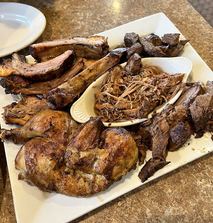 Meat paradise on a plate! This platter showcases the kitchen's greatest hits &ndash; ribs with perfect "tug," pulled pork, and chicken with skin crispier than morning gossip.