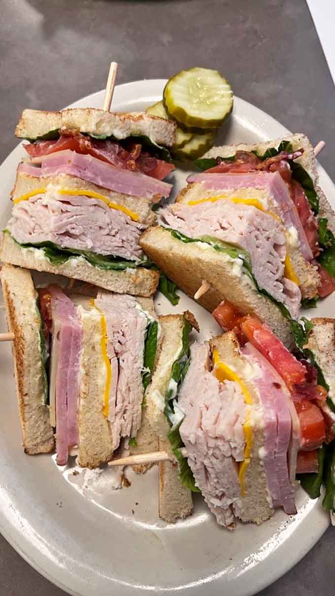 This towering club sandwich stacks turkey, bacon, and fresh vegetables between toasted bread like a edible skyscraper of satisfaction.