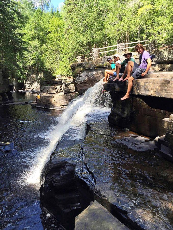 Adventure seekers find the perfect perch above cascading waters, their dangling feet framing nature's perfect photo opportunity.