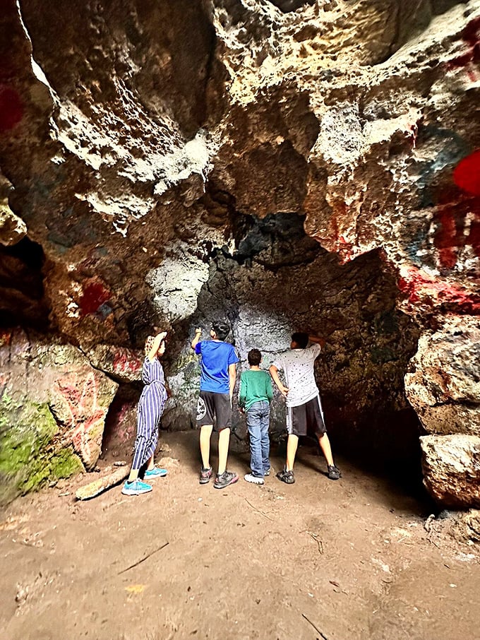 Explorers examine the cave's inner chambers, where generations of visitors have left their colorful marks against ancient limestone walls.