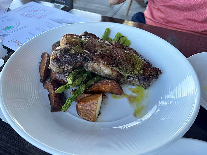 A perfectly cooked steak rests beside roasted potatoes and fresh asparagus &ndash; simple ingredients elevated through expert preparation.