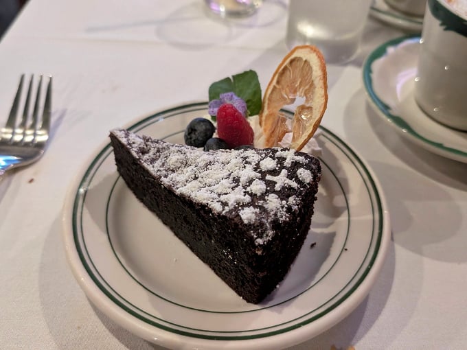 This slice of Torta Caprese isn't just chocolate cake &ndash; it's a dense, flourless love letter to cocoa, dusted with powdered sugar and adorned with fresh berries.